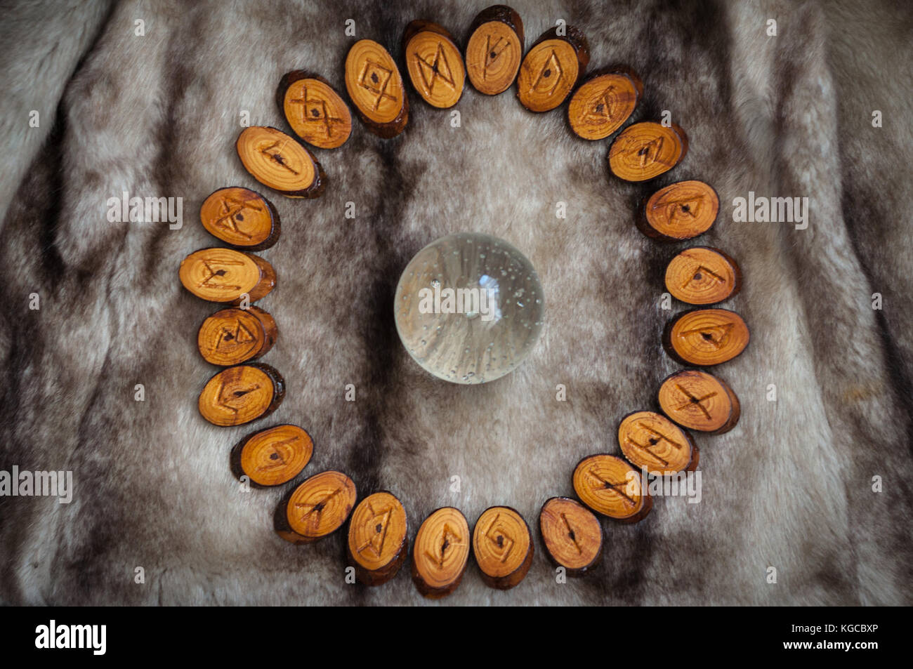 wood runes handmade fur are lying beside the crystal ball and semi ...