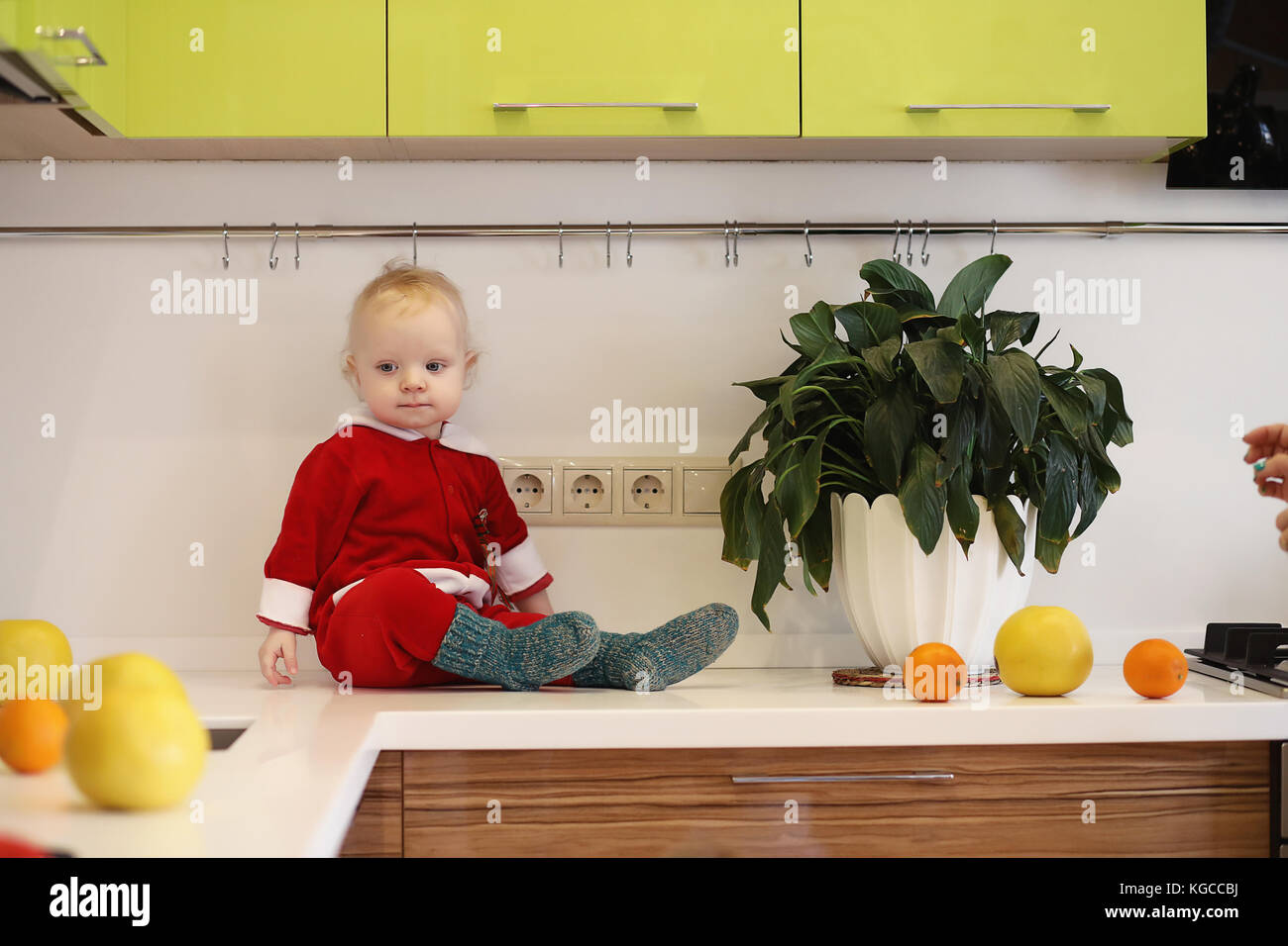 Little child in the kitchen sits on a table Stock Photo - Alamy