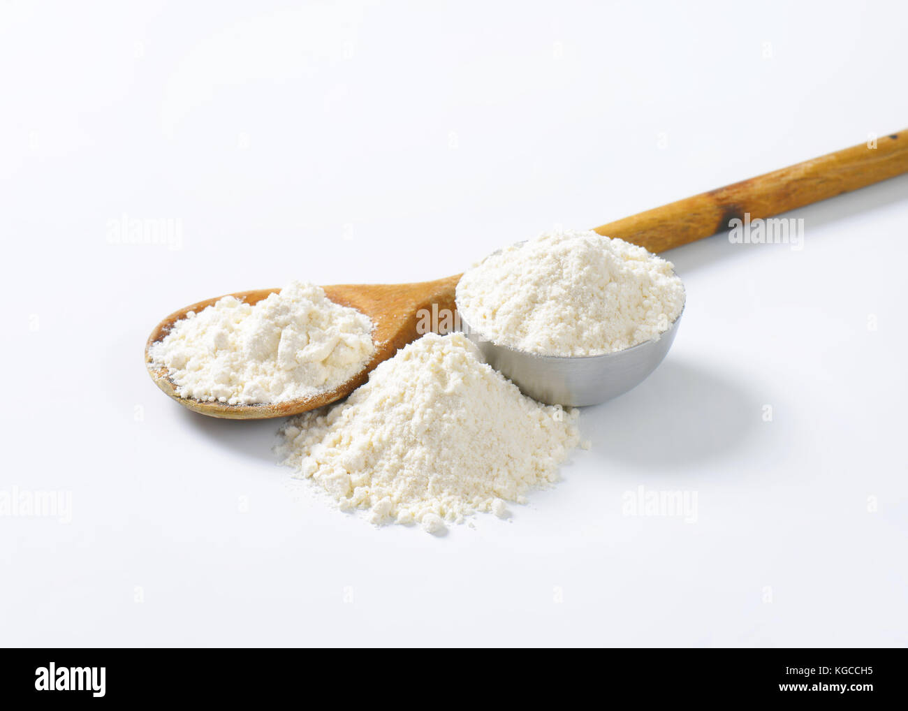 soft wheat flour on wooden spoon and in metal bowl on white background ...