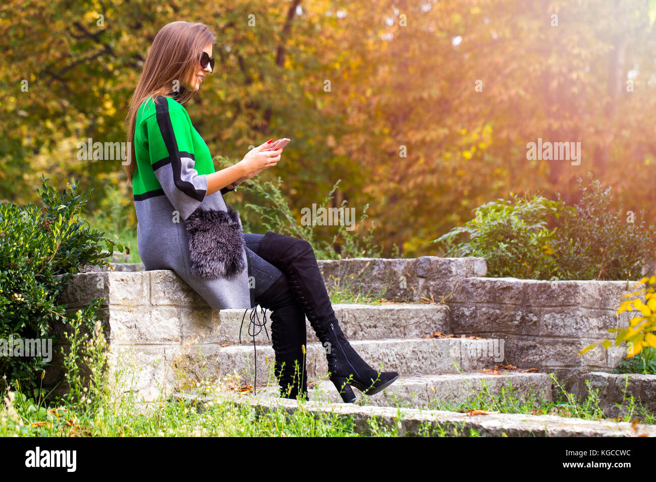 Beautiful woman checks her messages in the park Stock Photo - Alamy