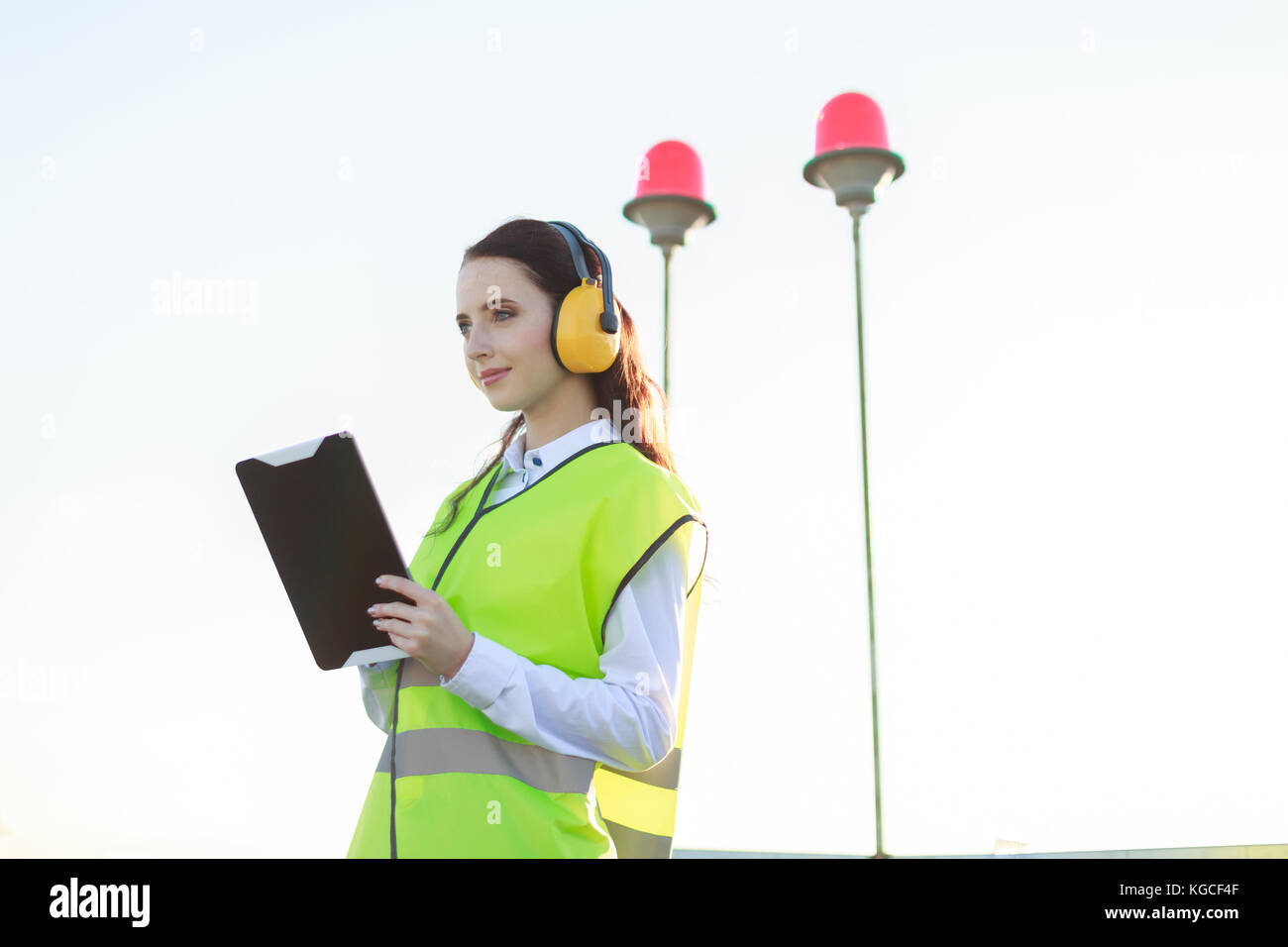 Young woman in green west and earmuffs stand on roof, hold tablet Stock ...