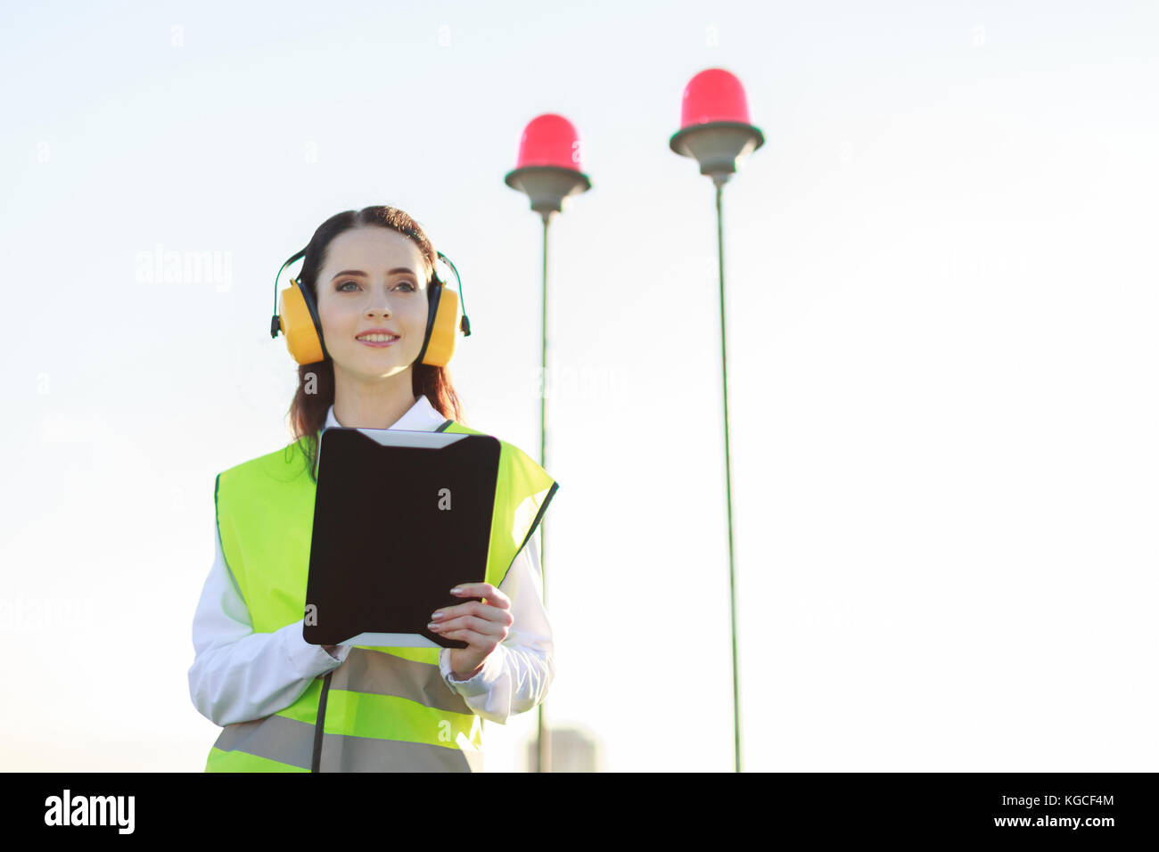 Young woman in green west and earmuffs stand on roof, hold tablet Stock ...