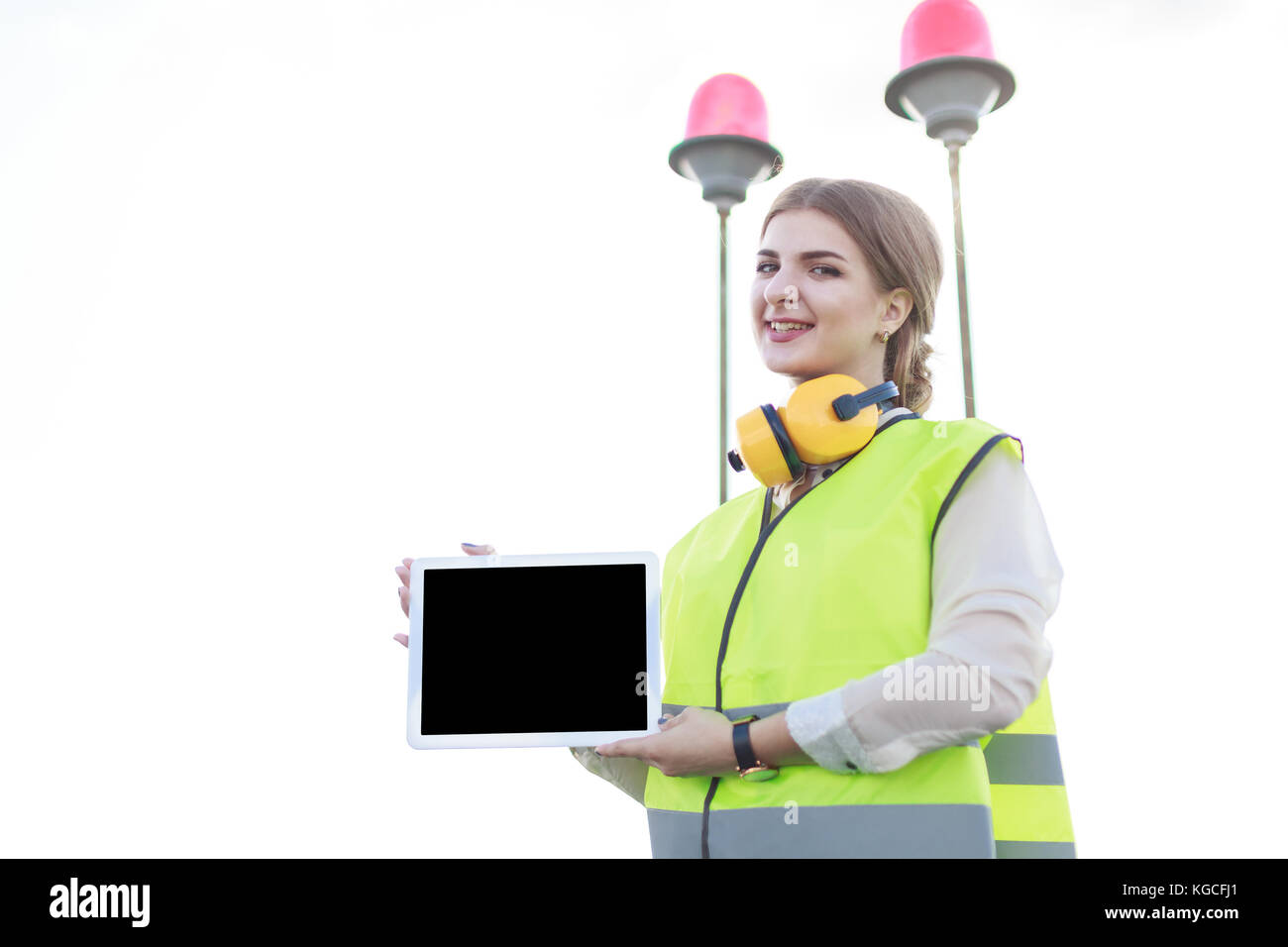 Young pretty woman in green west and earmuffs stand on roof and show ...