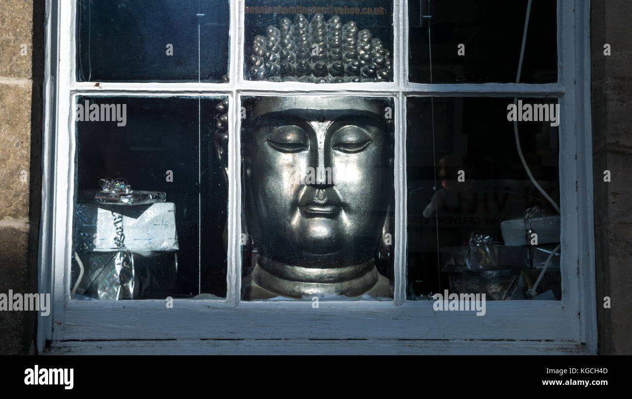Silver buddha head seen through sash and case shop window display with ...