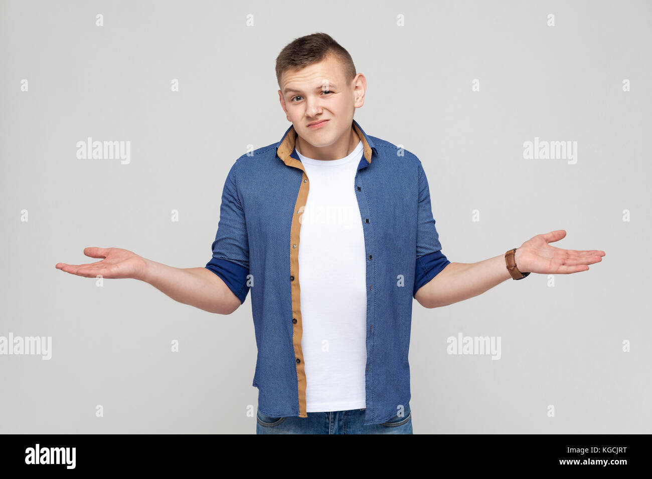 Confused young man looking at camera. Studio shot, gray background ...