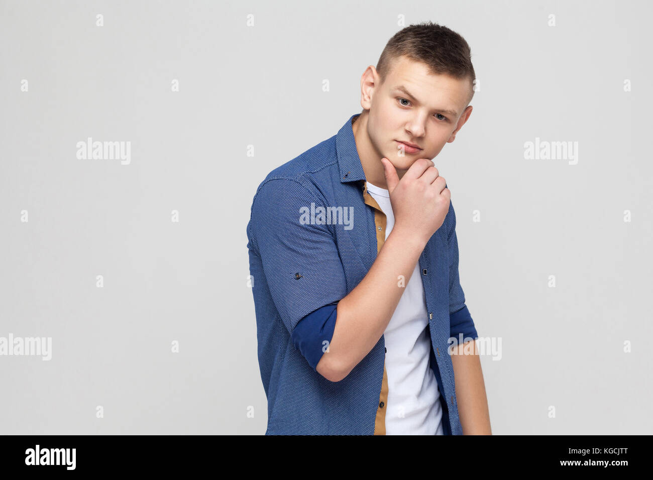 Choosing. Pondering boy looking down and thinking. Studio shot, gray ...