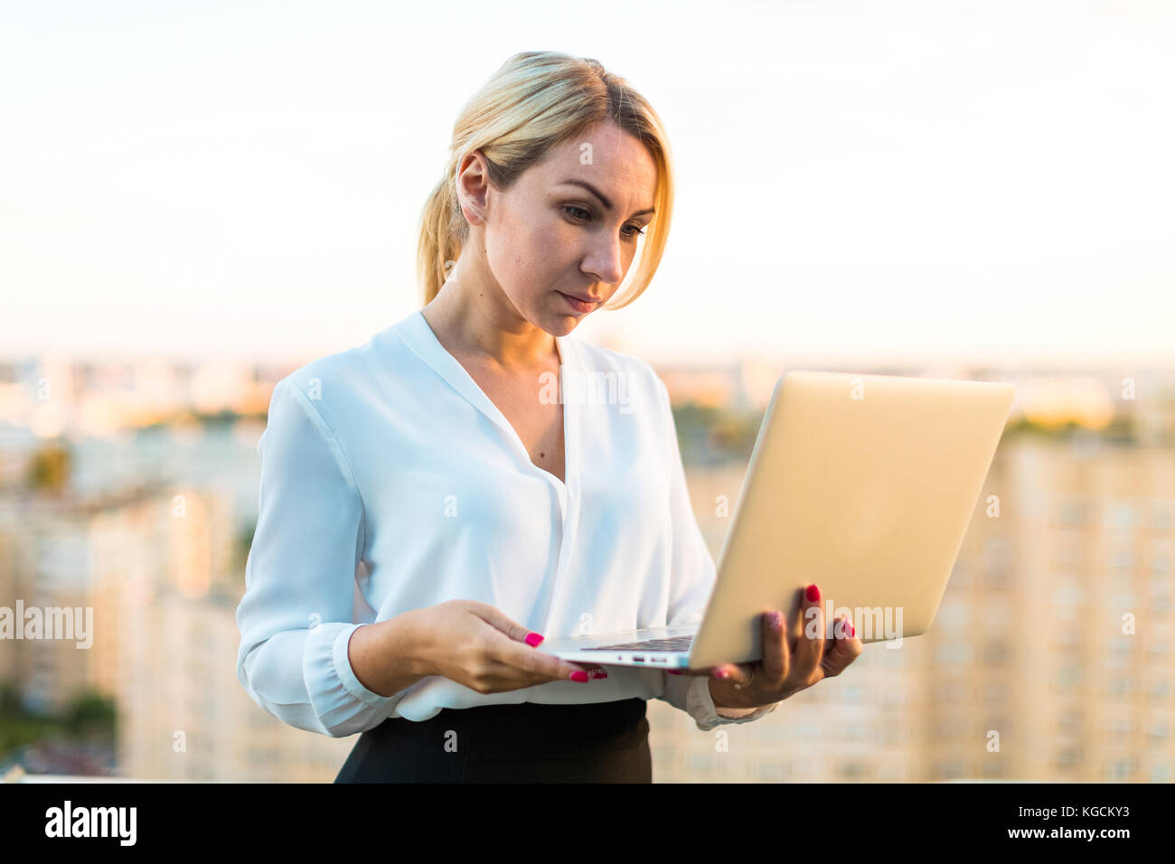Beautiful smart business lady stand on the roof with laptop in h Stock ...