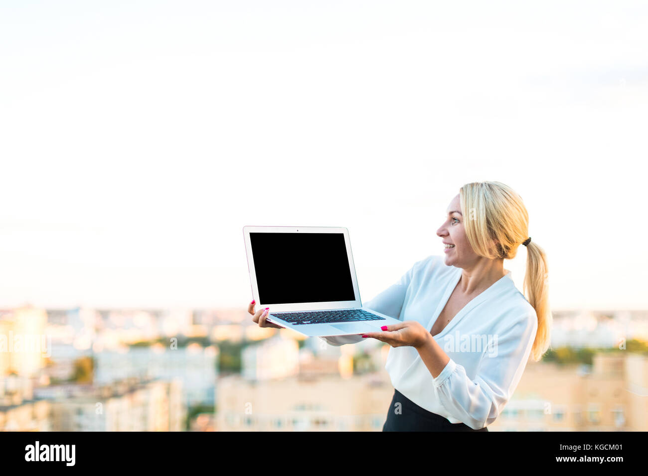 Beautiful smart business lady stand on the roof with laptop in h Stock ...