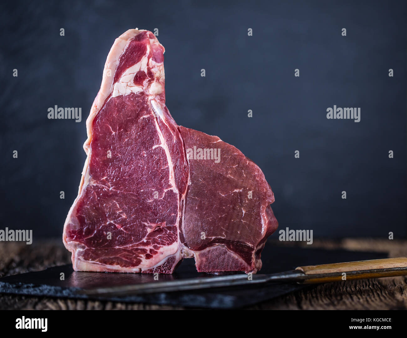 Beef steak T-bone. Raw beef steak T-bone on slate board with butcher ...