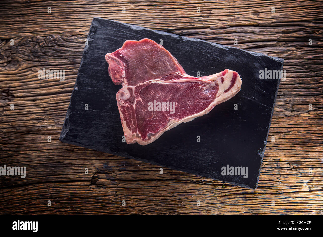Beef steak T-bone. Raw beef steak T-bone on slate board with butcher ...