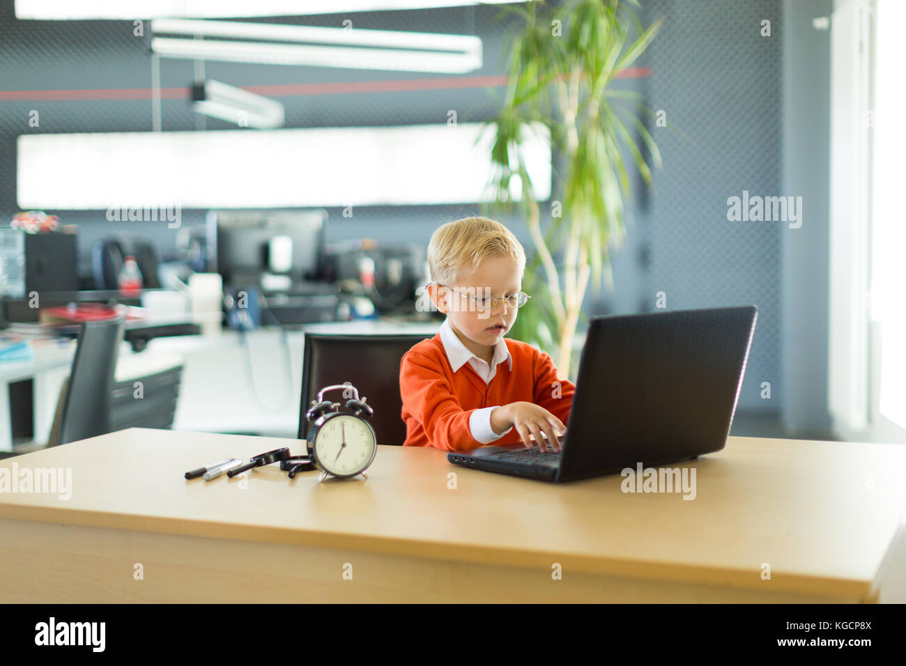 Cute boy sit at the desk in the office and uses computer Stock Photo ...
