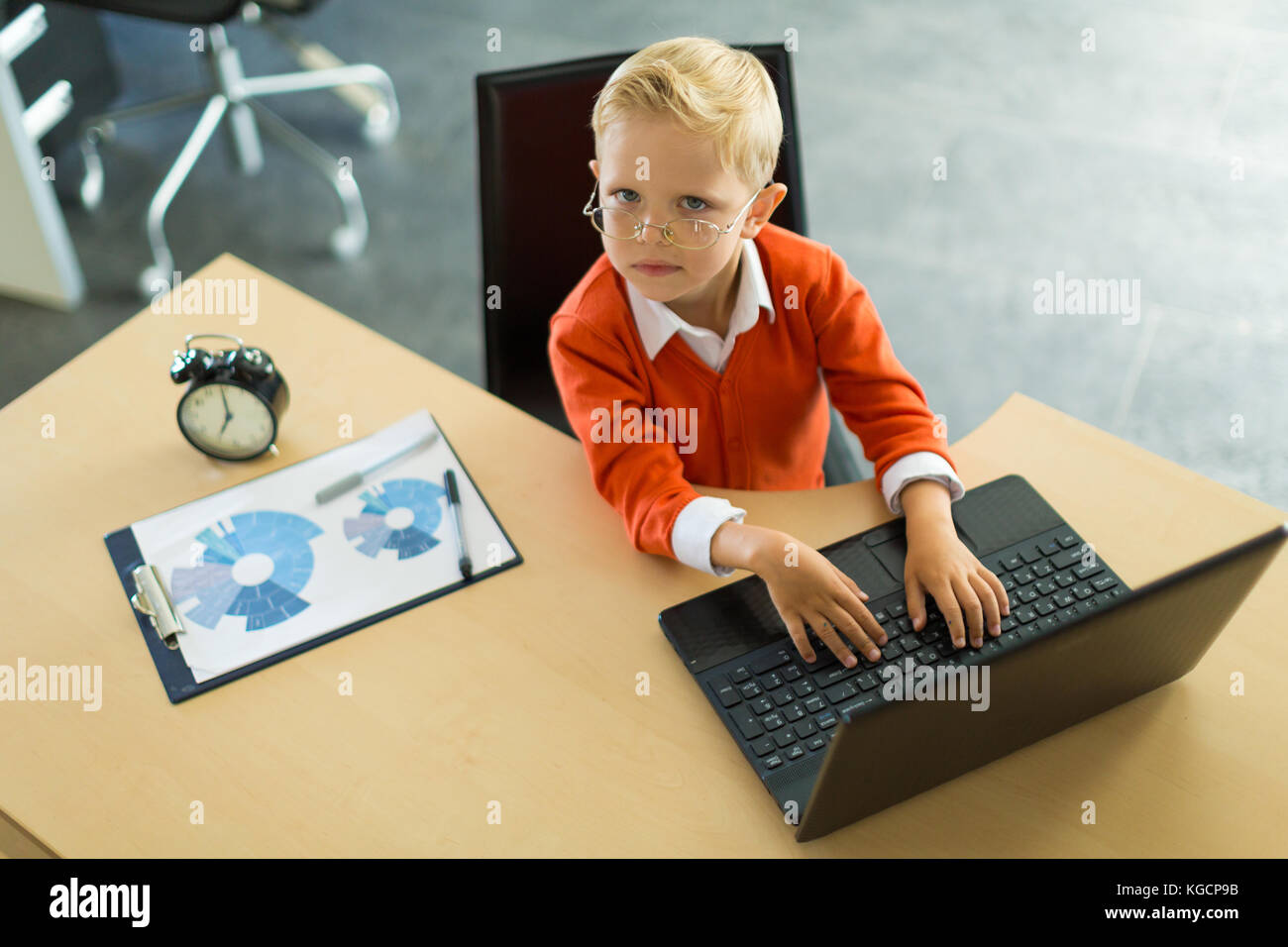 Cute boy sit at the desk in the office and uses computer Stock Photo ...