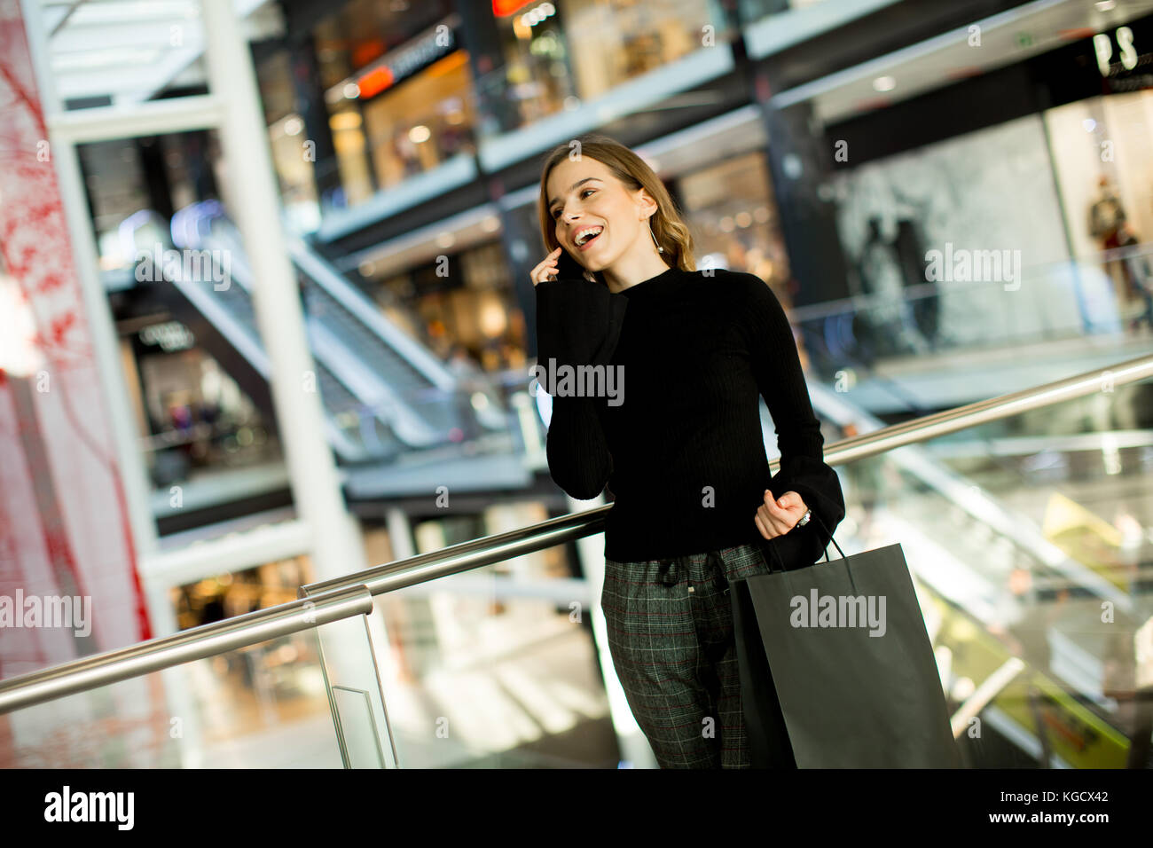 Young woman standing in shopping mall talking over mobile phone Stock ...