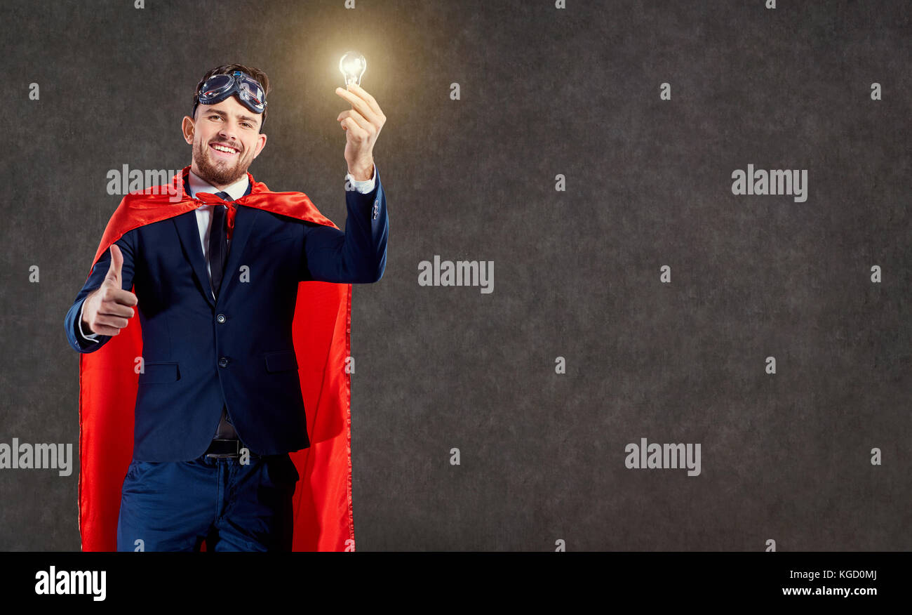 A businessman in a superhero costume with a glowing light bulb in his ...
