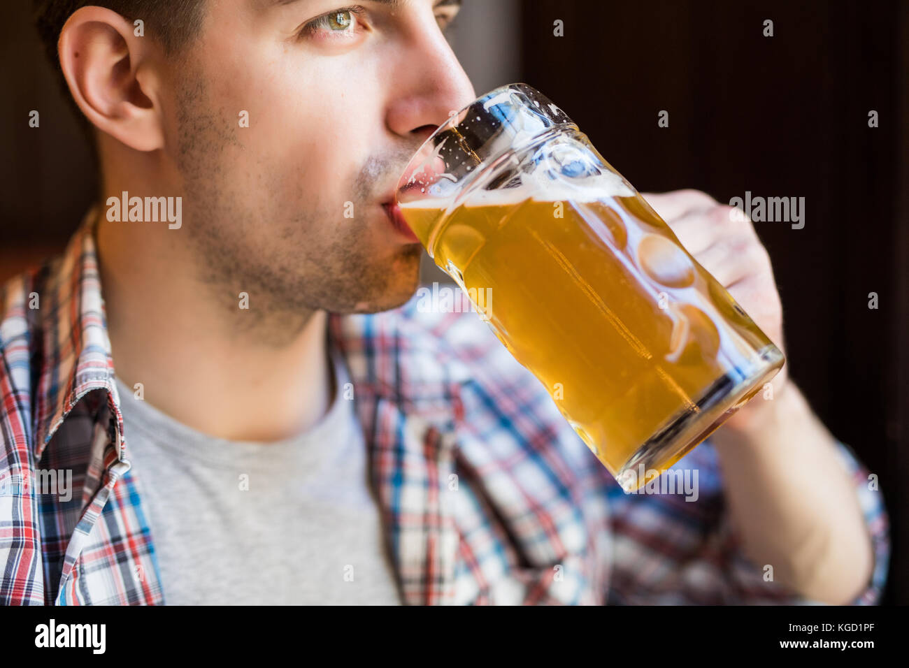Man drinking beer. Side view of handsome young man drinking beer while ...