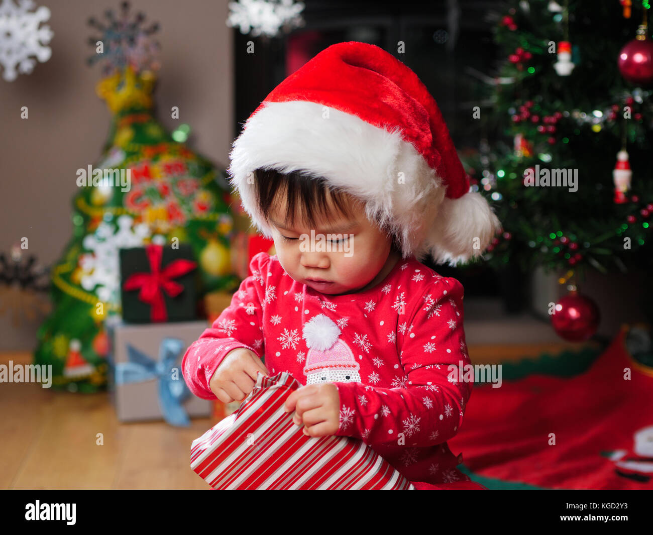 Santa baby girl opening her Christmas gift Stock Photo - Alamy