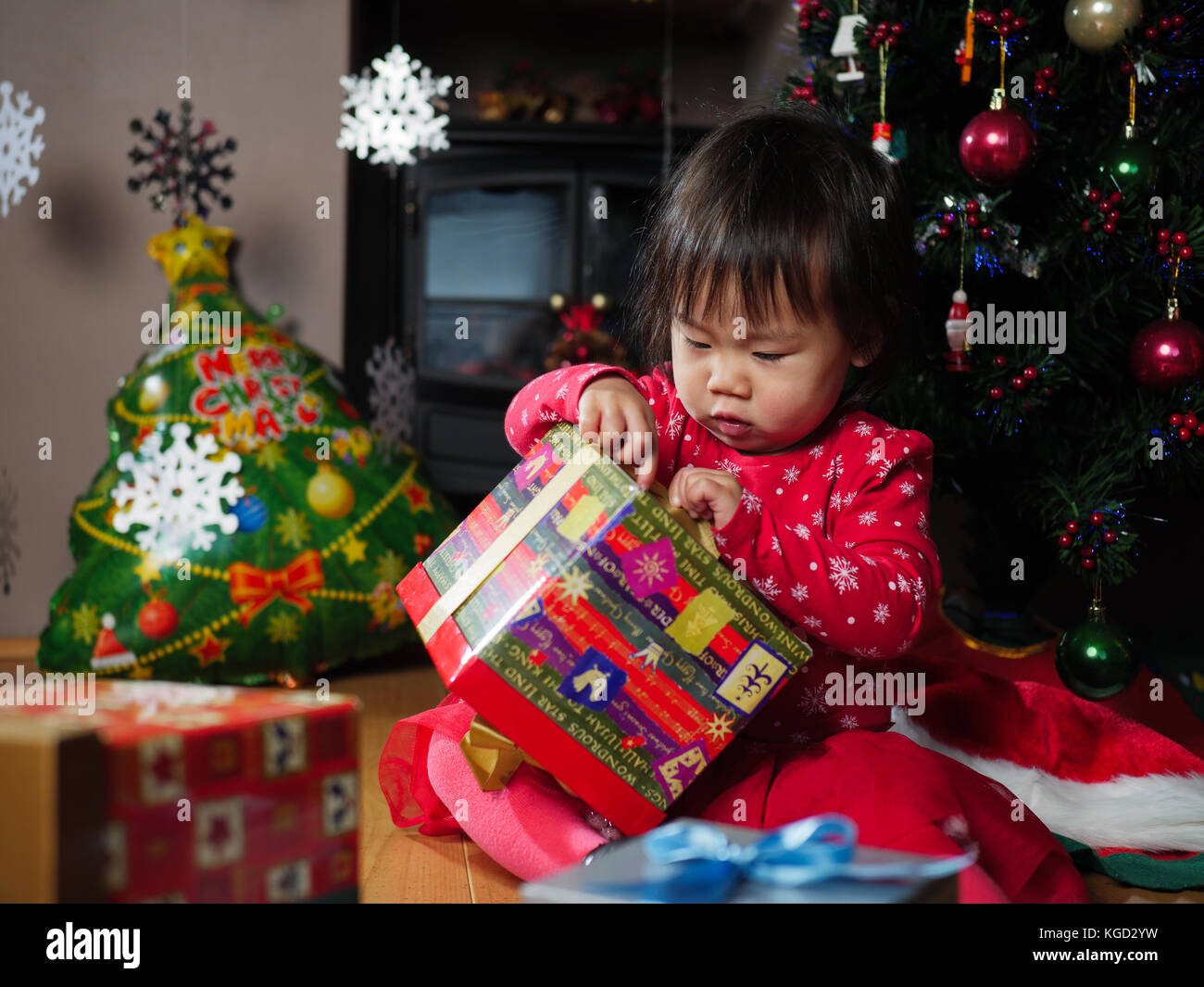 Santa baby girl opening her Christmas gift Stock Photo - Alamy