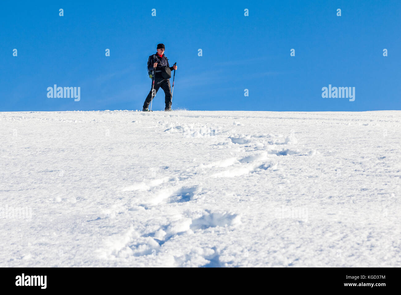 Man is snowshoe hiking through deep snow on sunny day Stock Photo - Alamy