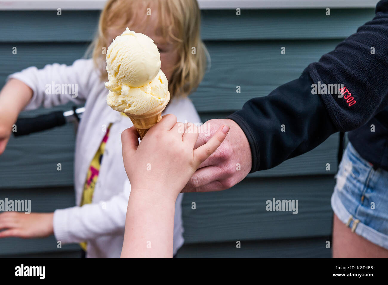 An adult giving an ice cream cone to a child Stock Photo - Alamy