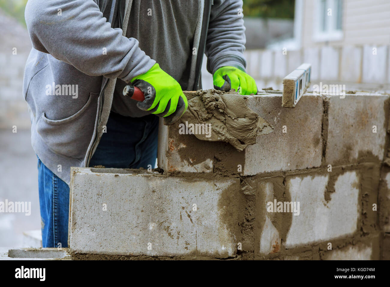 Mason lays down a wall of blocks Stock Photo - Alamy