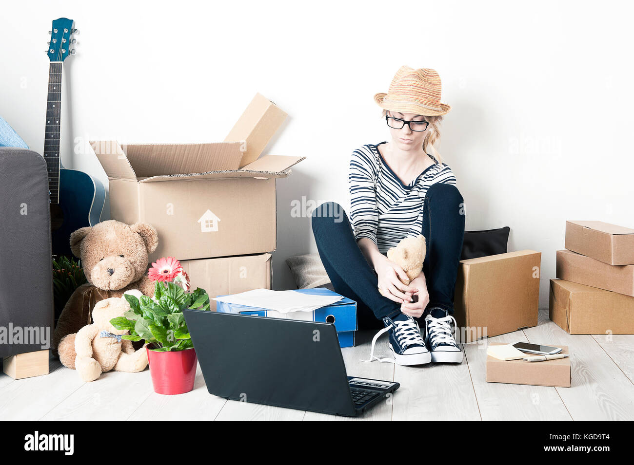 Moving house student girl sitting on the floor Stock Photo - Alamy