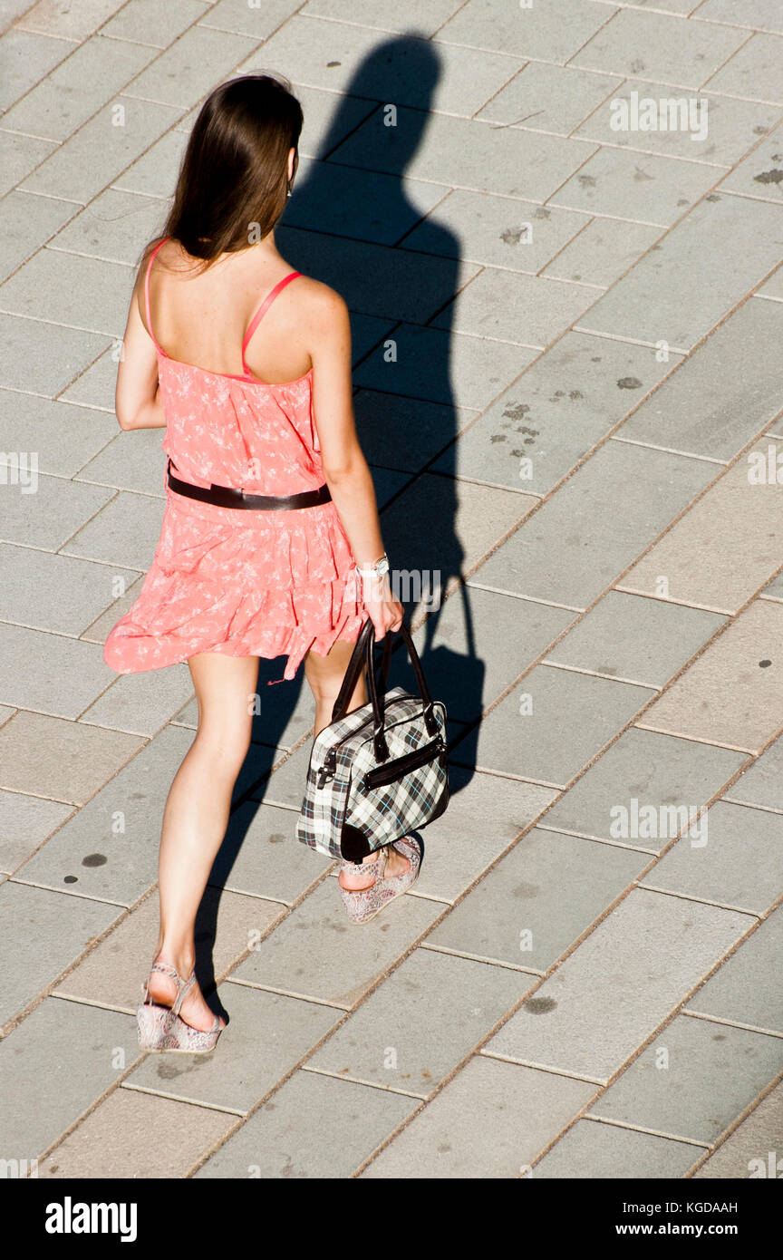 young woman in summer dress walking in the street in a warm sunny day ...