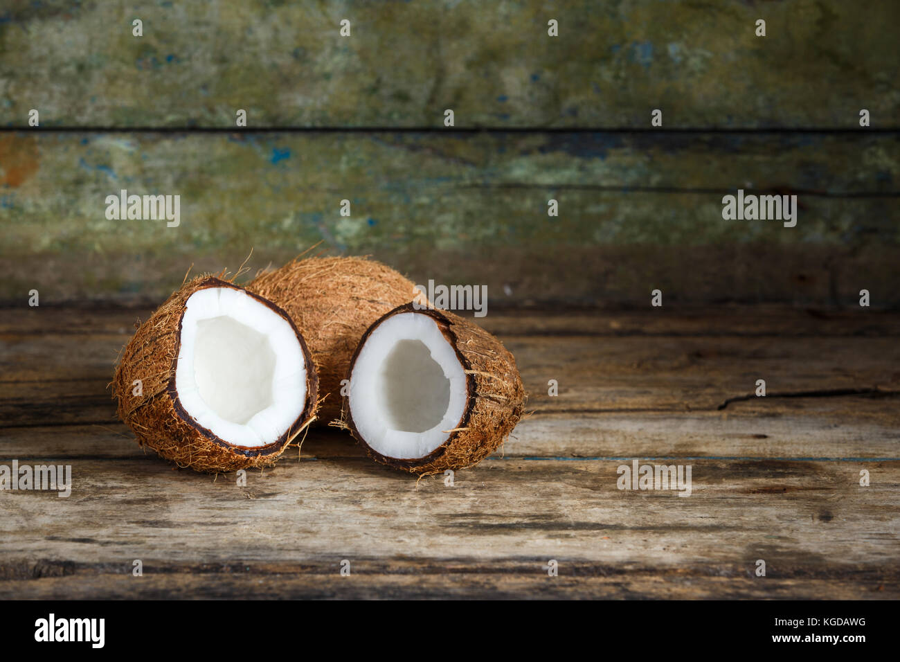 Fresh whole and cut in half coconuts on wooden background with copy ...