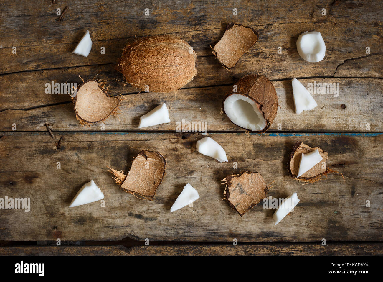 Fresh coconuts with spreaded chops and shell parts on wooden background ...