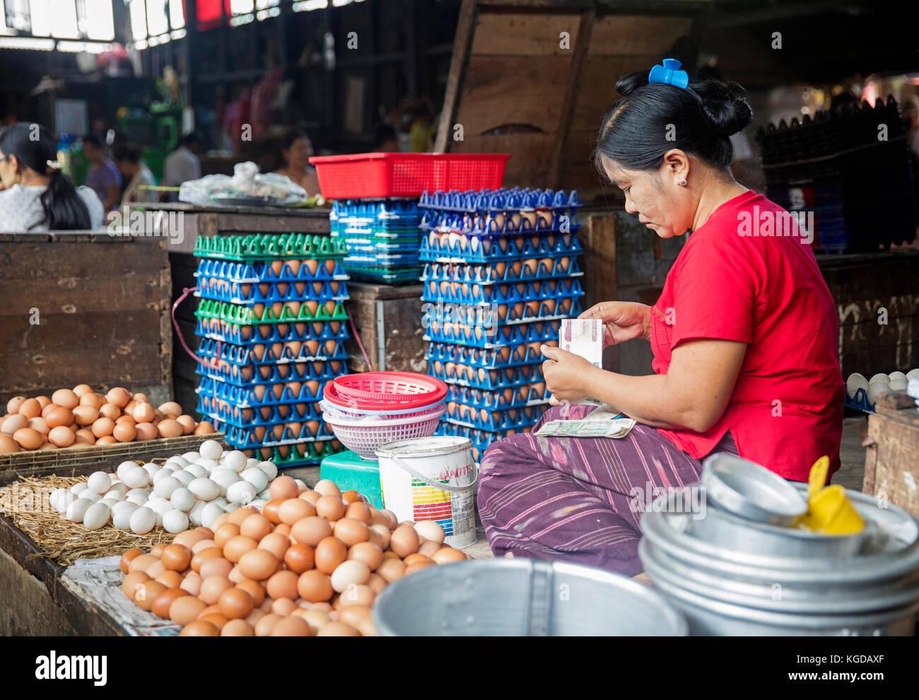 Burmese woman selling eggs and counting money at food market in Yangon ...