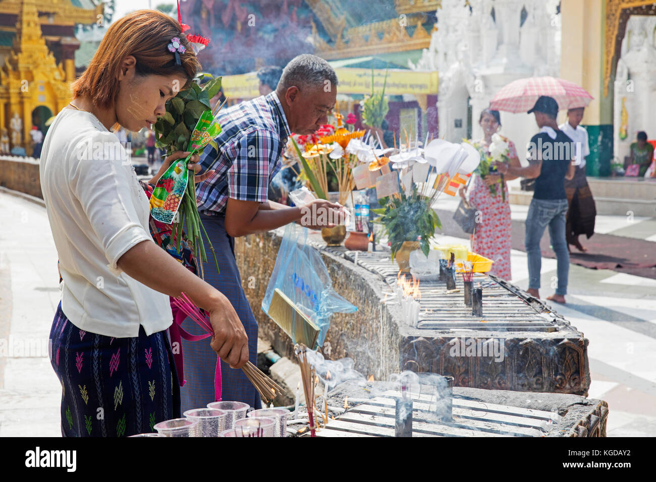 Burmese girl lighting incense sticks at the Shwedagon Pagoda / Golden ...