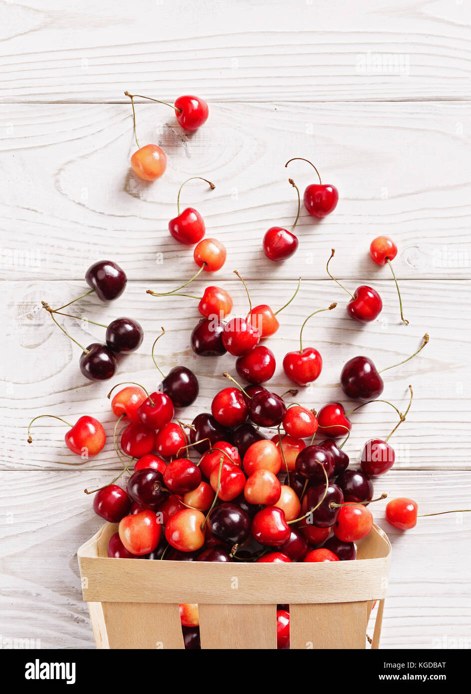 Cherry explosion. Photo of cherry in basket on white wooden table. Top ...