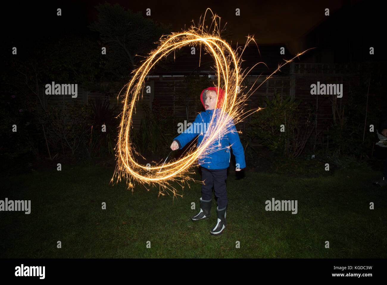 Boy with hand held sparkler firework in a residential garden on Bonfire ...