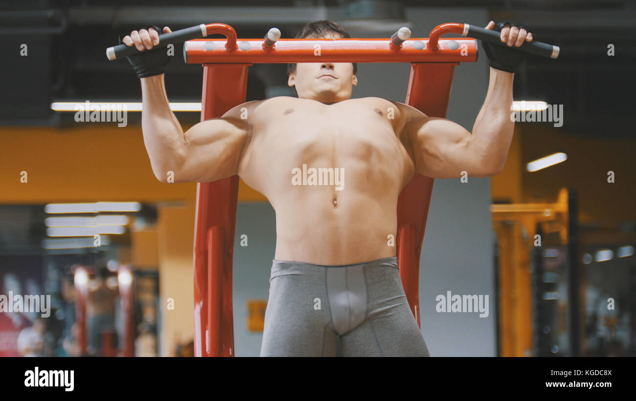 Muscular young man pulling up in a gym, close up Stock Photo - Alamy