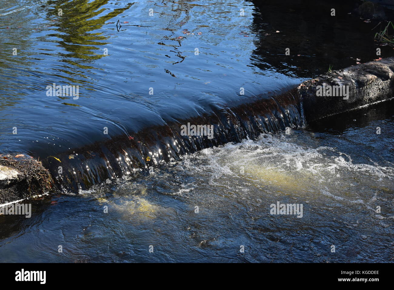 Flowing river with water falling over a fish step at mill site creating ...