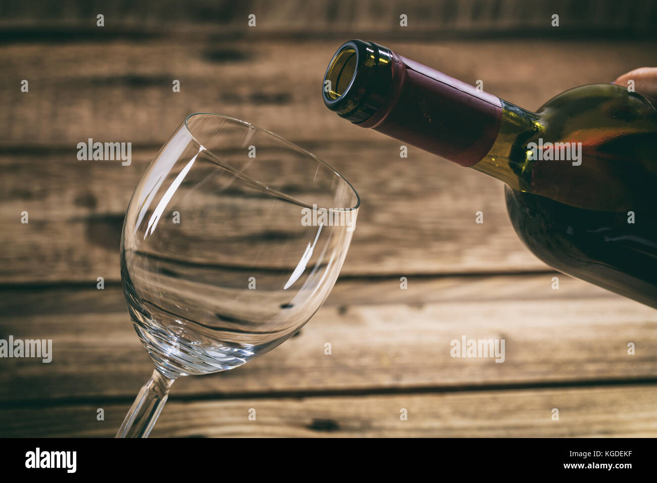 Pouring wine in an empty glass on a wooden table Stock Photo - Alamy