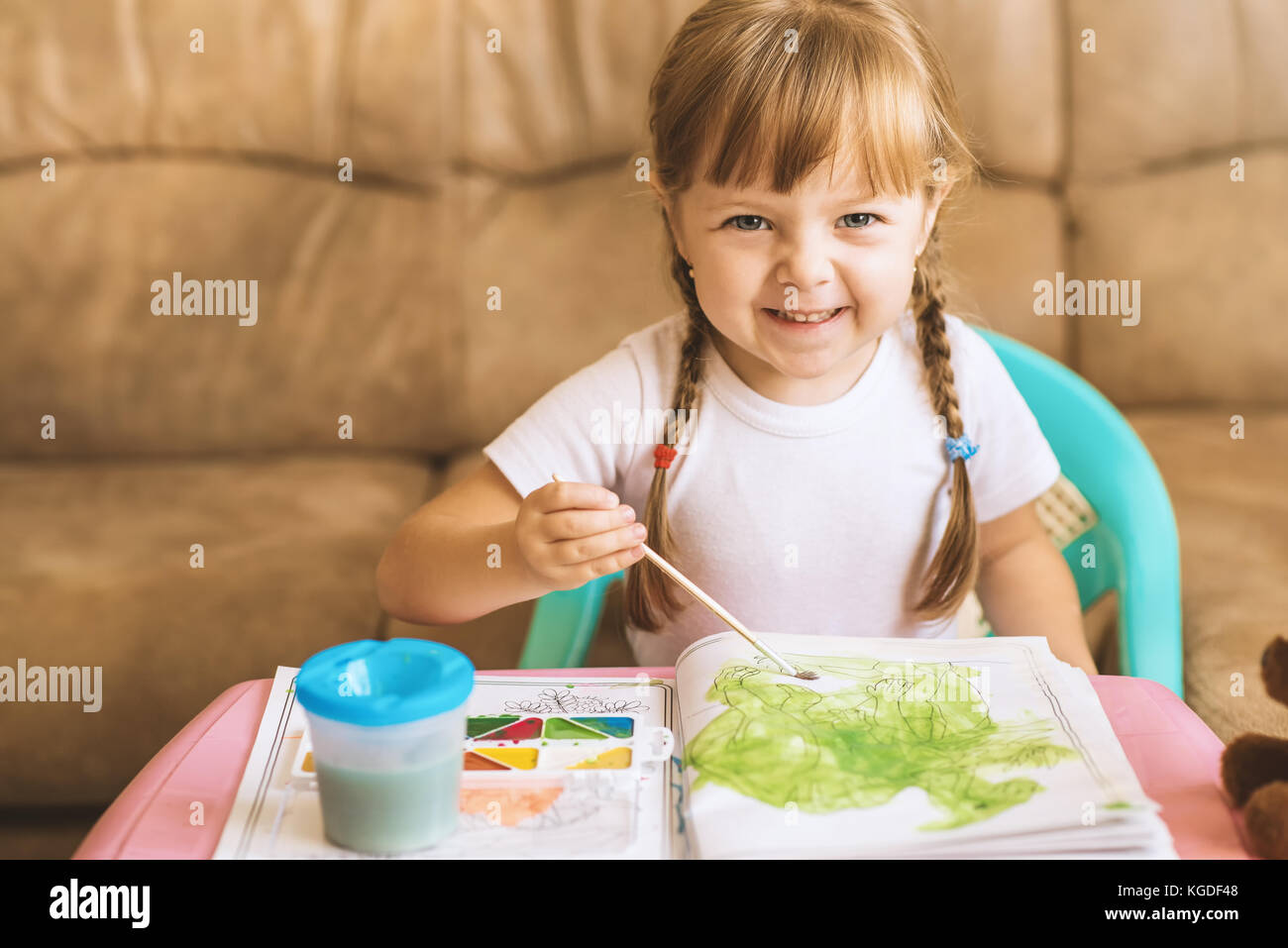 Little girl coloring drawings sitting at the table, child development ...