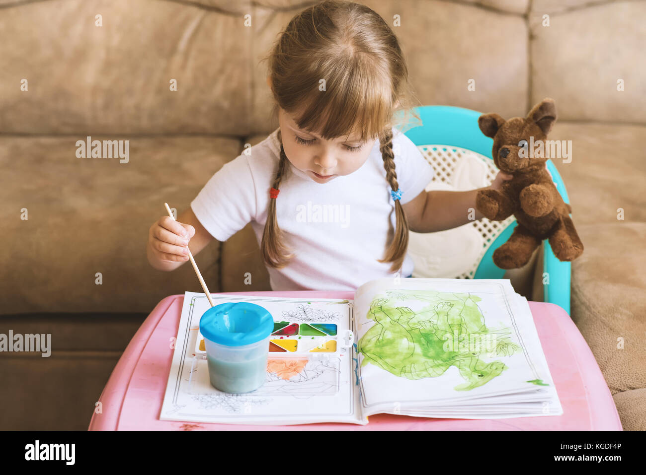 Little girl coloring drawings sitting at the table, child development ...