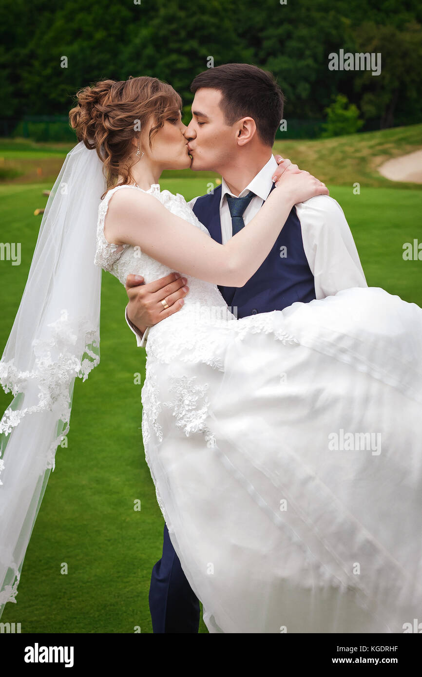 Groom holding bride on arms, hugging and kissing her in nature Stock ...