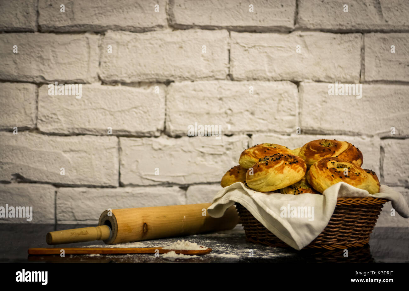 Fresh homemade buns on basket with rustic white brick background. Close ...