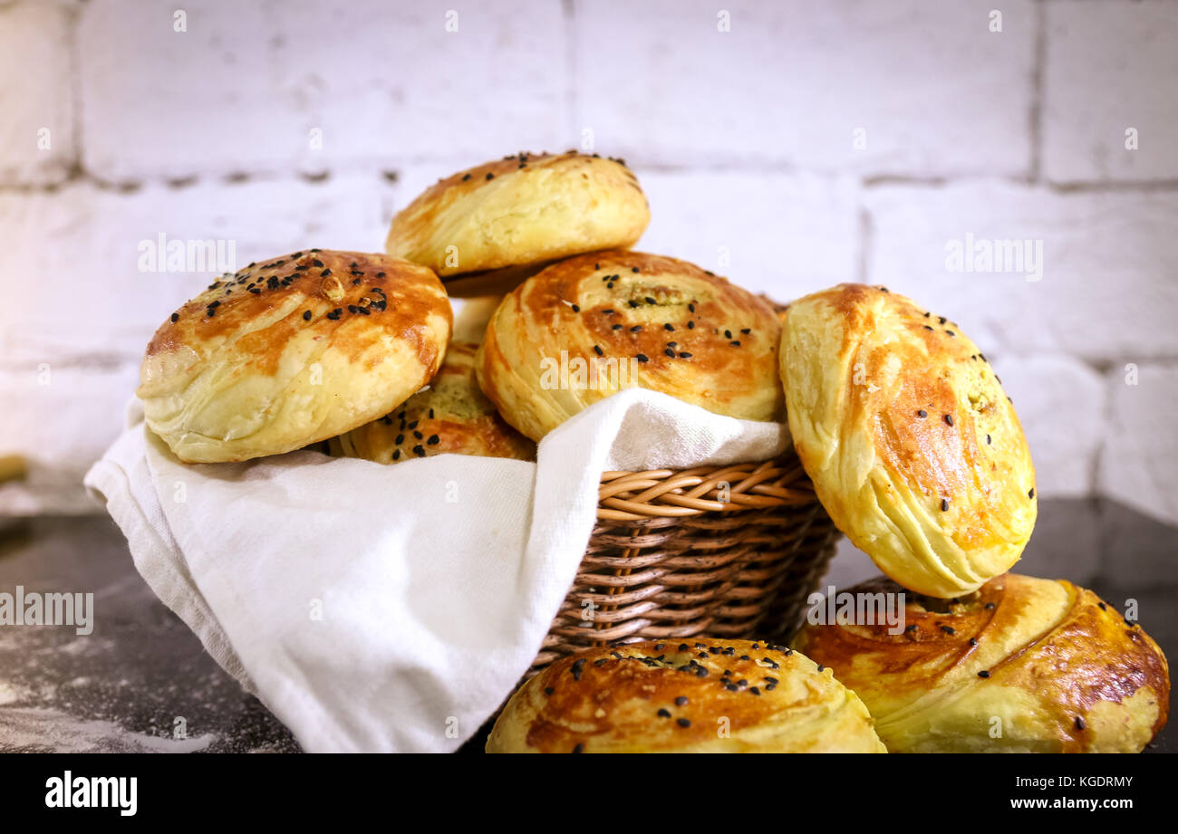 Fresh homemade buns on basket with rustic white brick background. Close ...