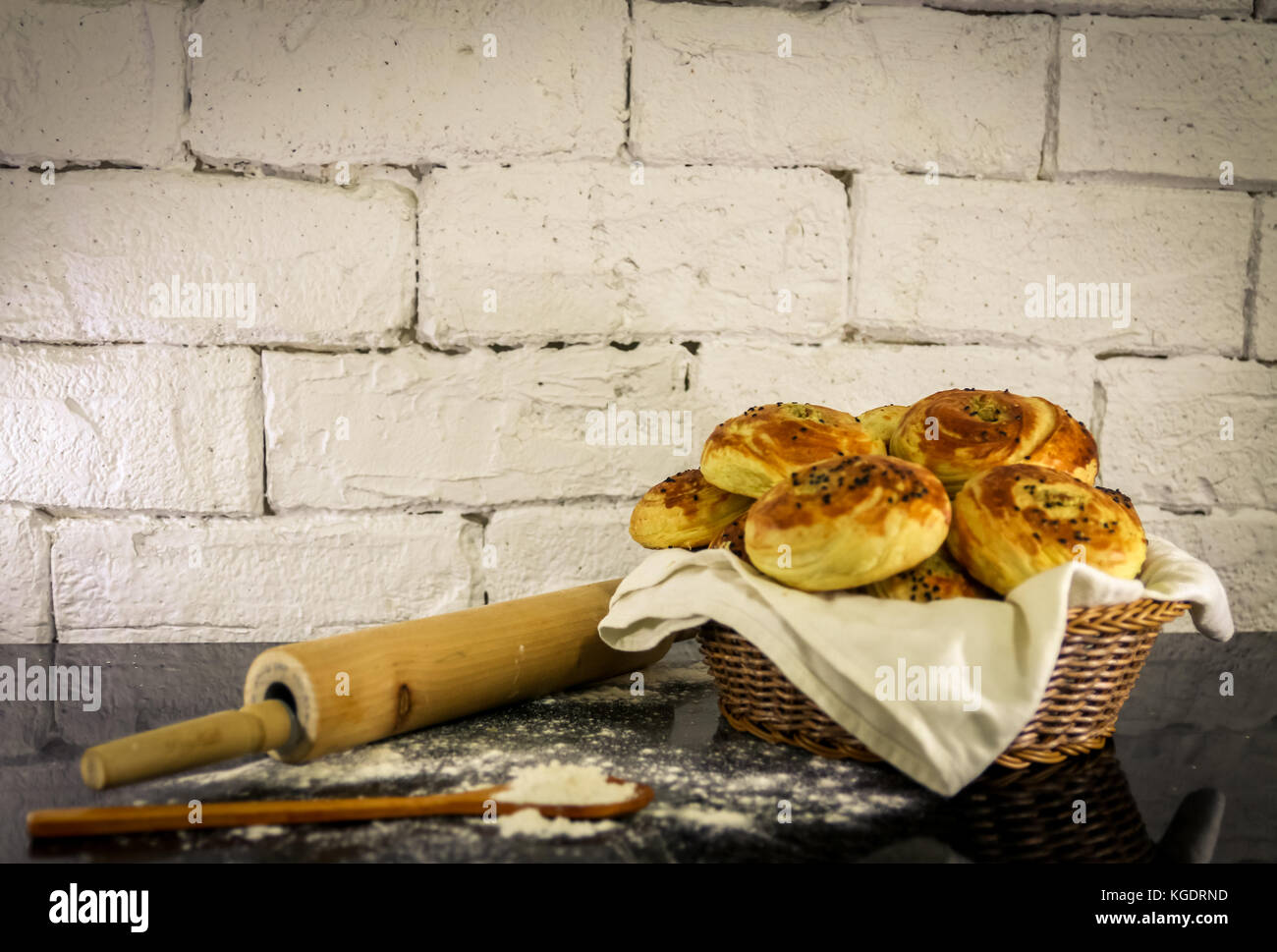 Fresh homemade buns on basket with rustic white brick background. Close ...