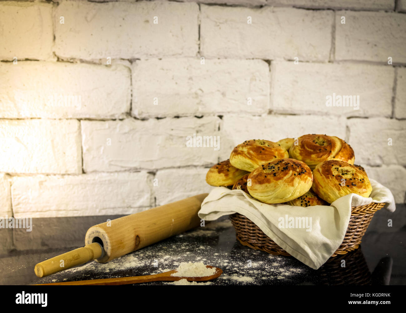 Fresh homemade buns on basket with rustic white brick background. Close ...