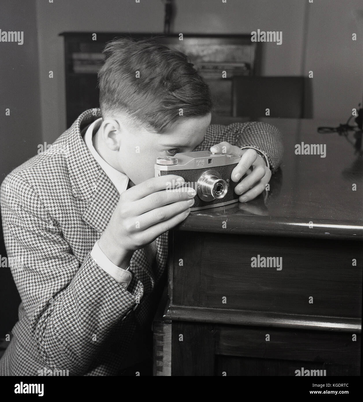 1950s, historical, young man using a corner of a cabinet for stability ...