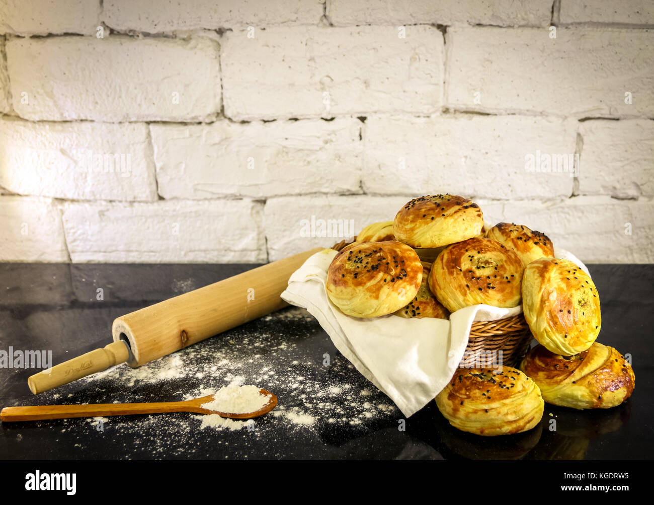 Fresh homemade buns on basket with rustic white brick background. Close ...