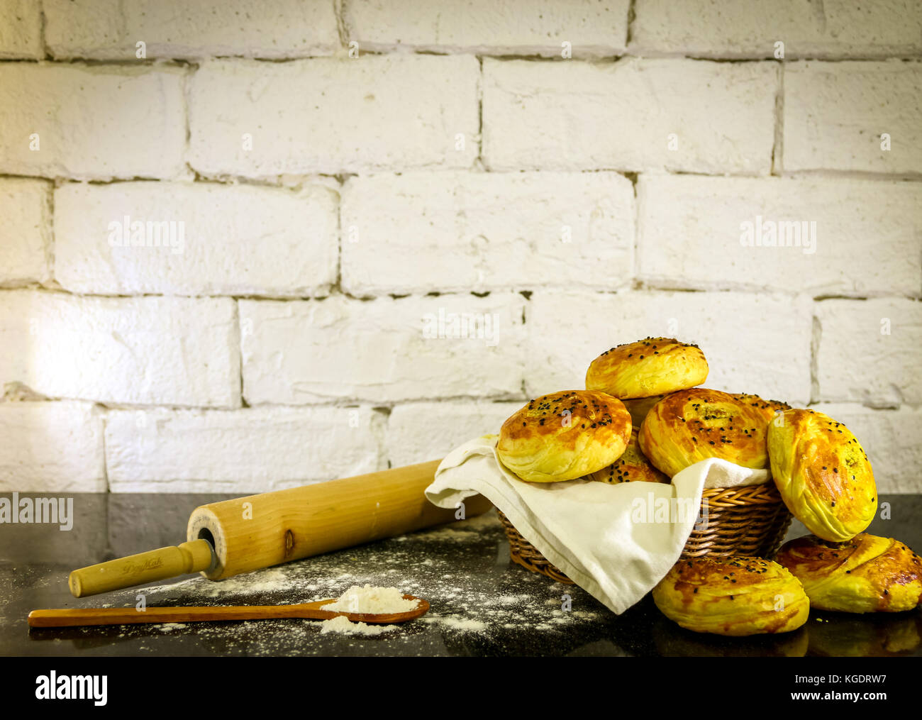 Fresh homemade buns on basket with rustic white brick background. Close ...