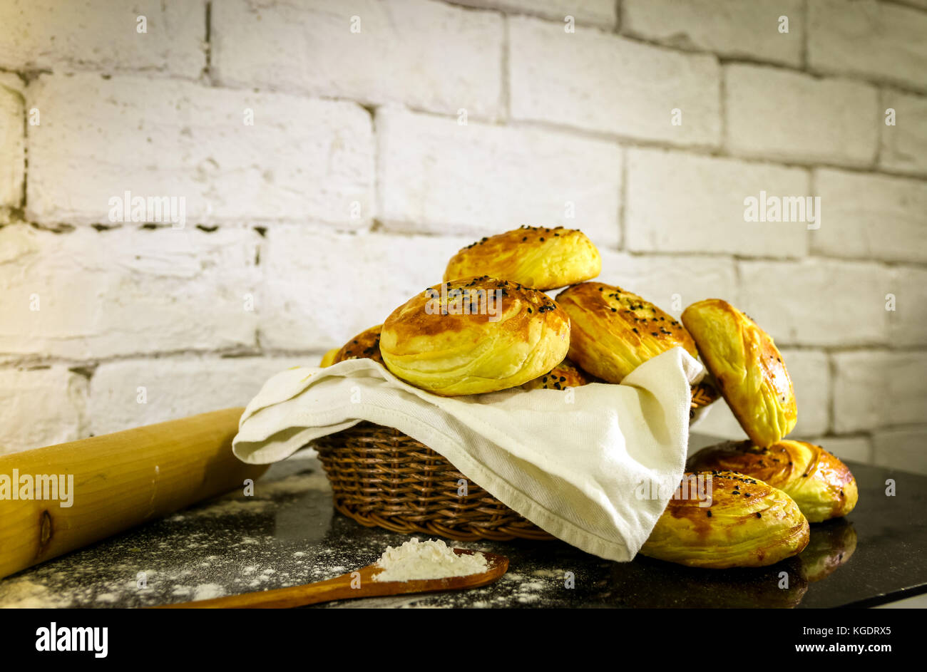 Fresh homemade buns on basket with rustic white brick background. Close ...