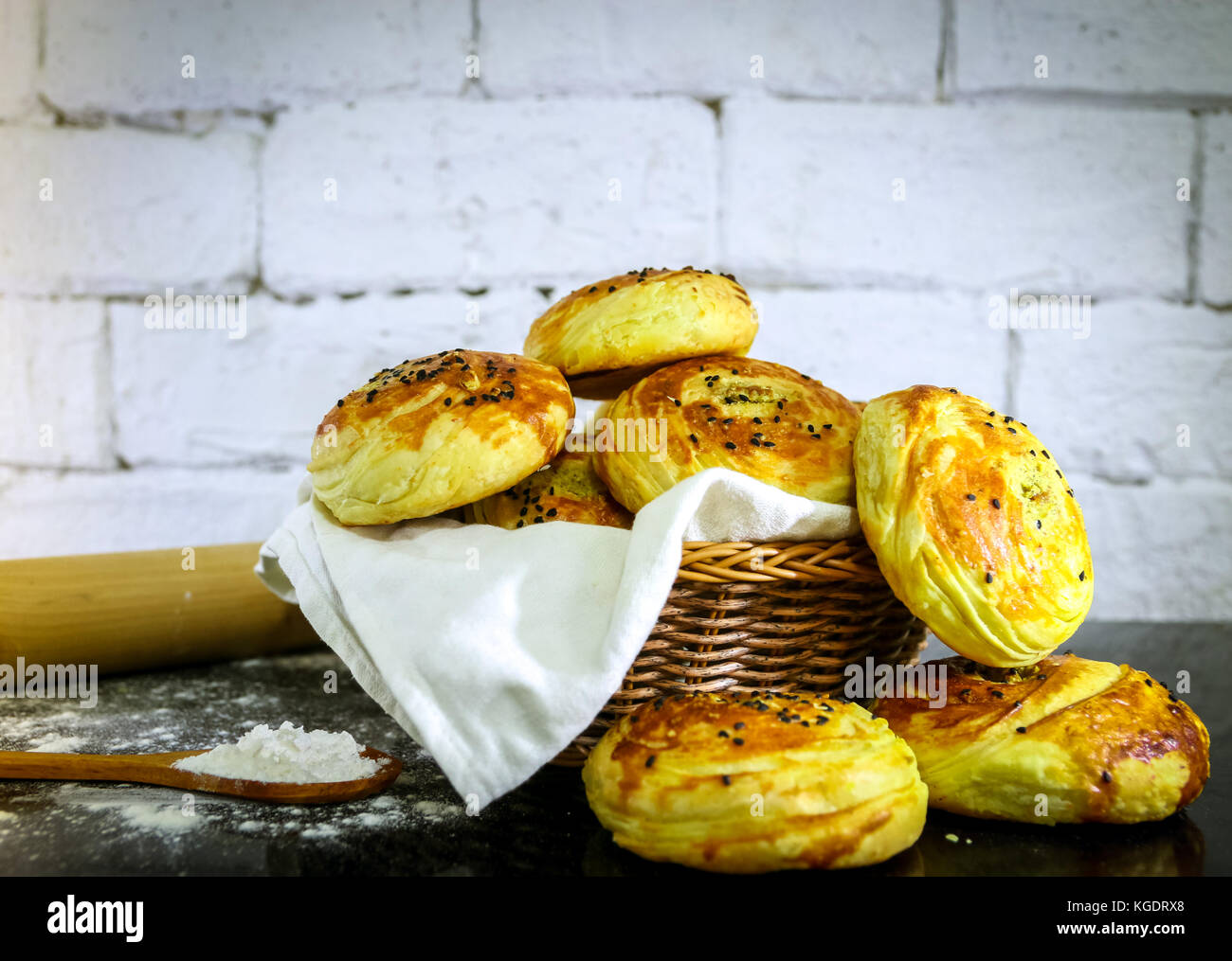 Fresh homemade buns on basket with rustic white brick background. Close ...