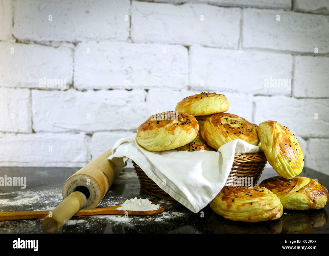 Fresh homemade buns on basket with rustic white brick background. Close ...