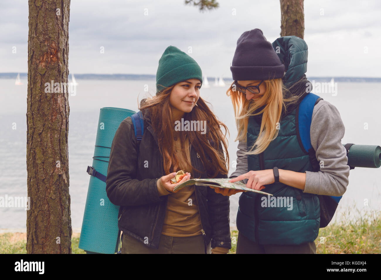 two woman with trendy look searching direction on location map while ...