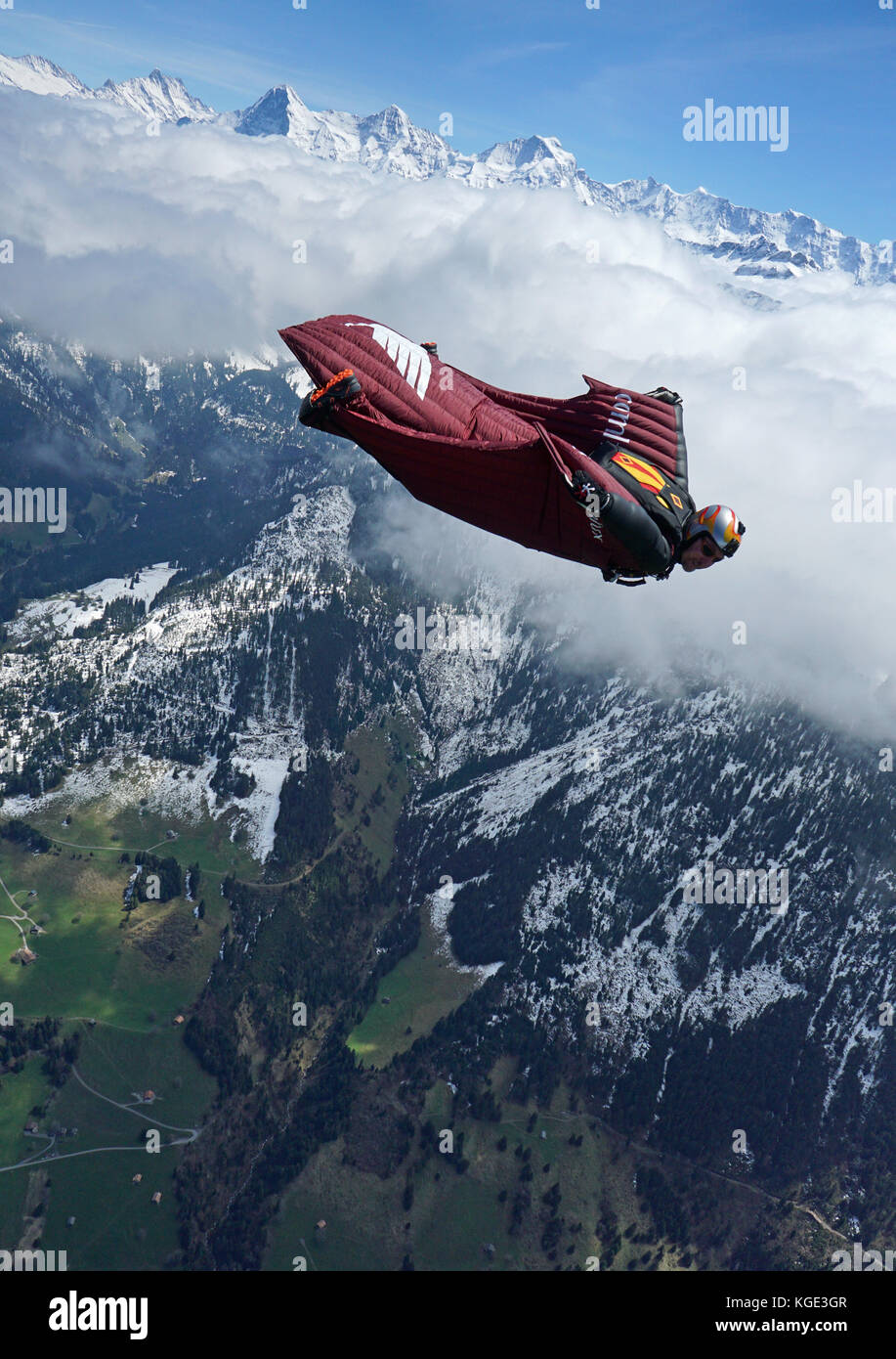 Wingsuit pilot is flying high in the sky over the Alps. Thereby the ...